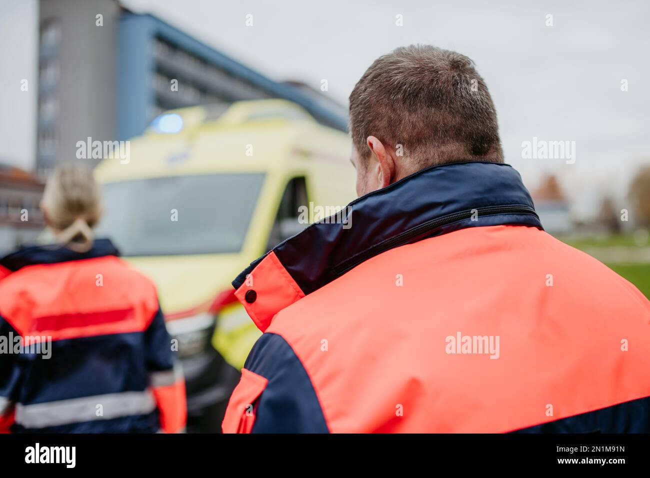 Rear view of rescuers getting in to ambulance car, preparing for rescue ...