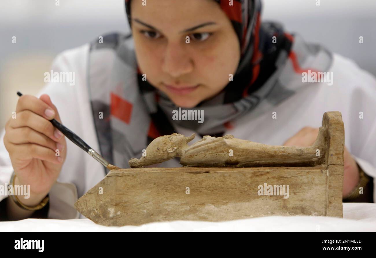 An Egyptian conservator works on an ancient Pharaonic wooden statue of ...