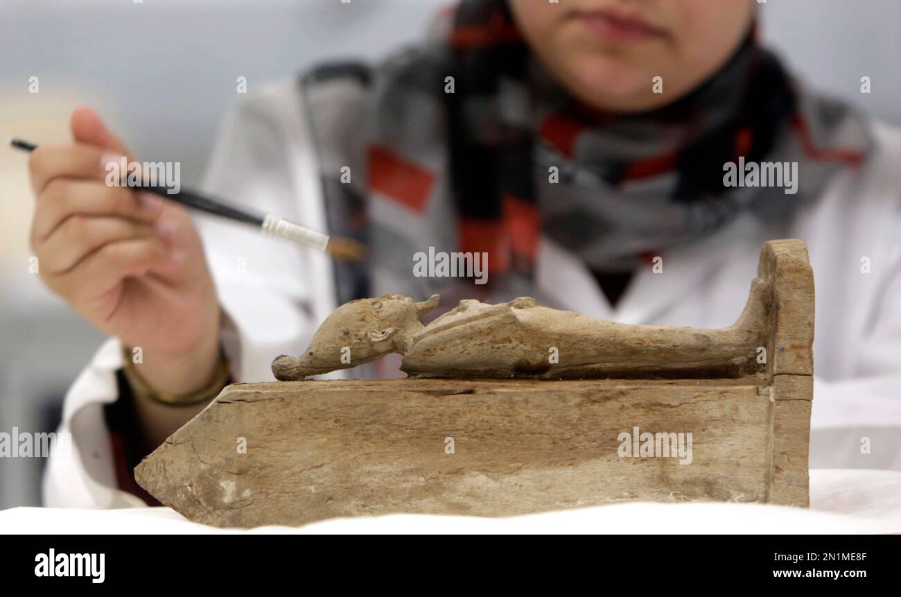 An Egyptian conservator works on an ancient Pharaonic wooden statue of ...