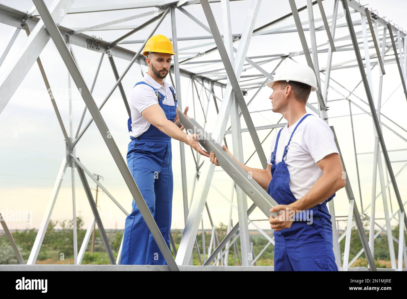 Workers building high voltage tower construction outdoors. Installation ...