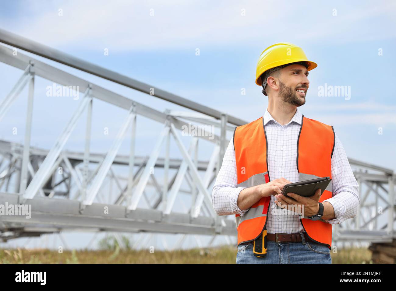 Professional engineer with tablet near high voltage tower construction ...
