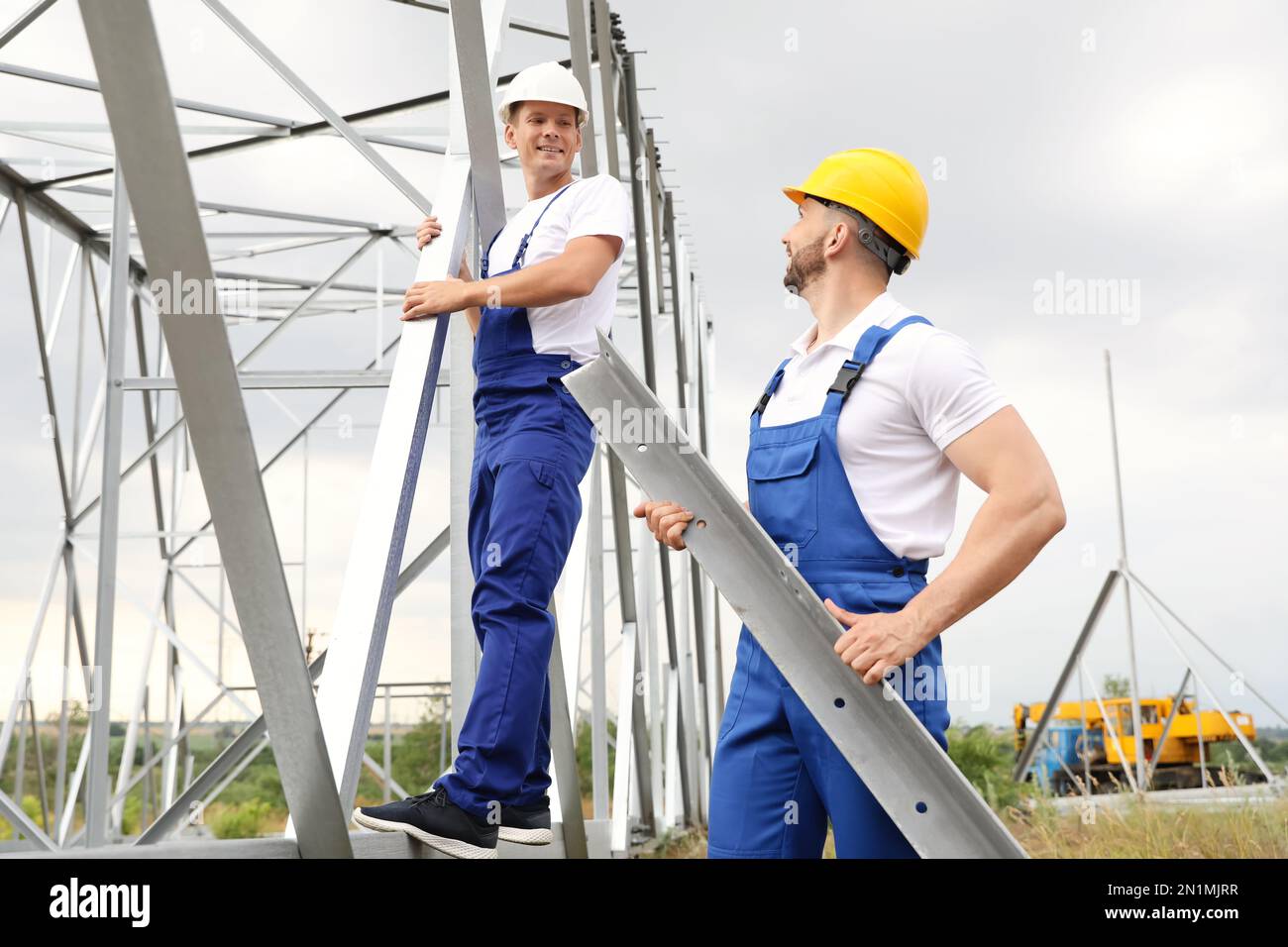 Workers building high voltage tower construction outdoors. Installation ...