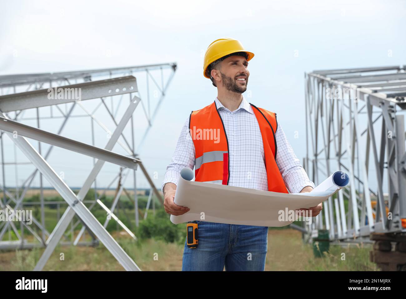 Professional engineer with plan near high voltage tower construction ...