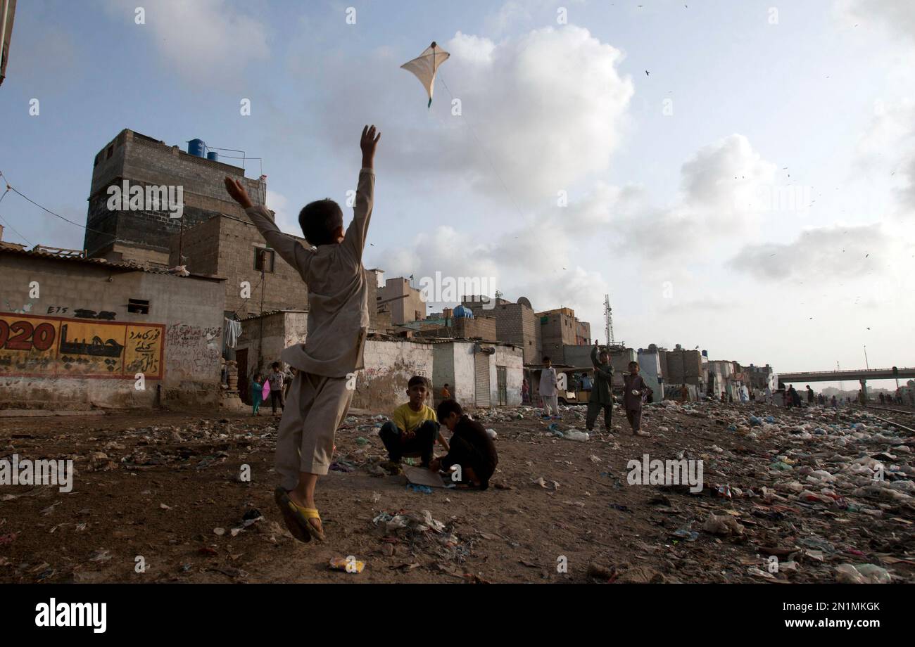 Pakistani children fly a kite in poor neighborhood in Karachi's slums ...