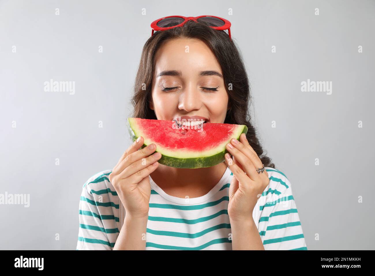 Beautiful young woman eating watermelon on grey background Stock Photo ...