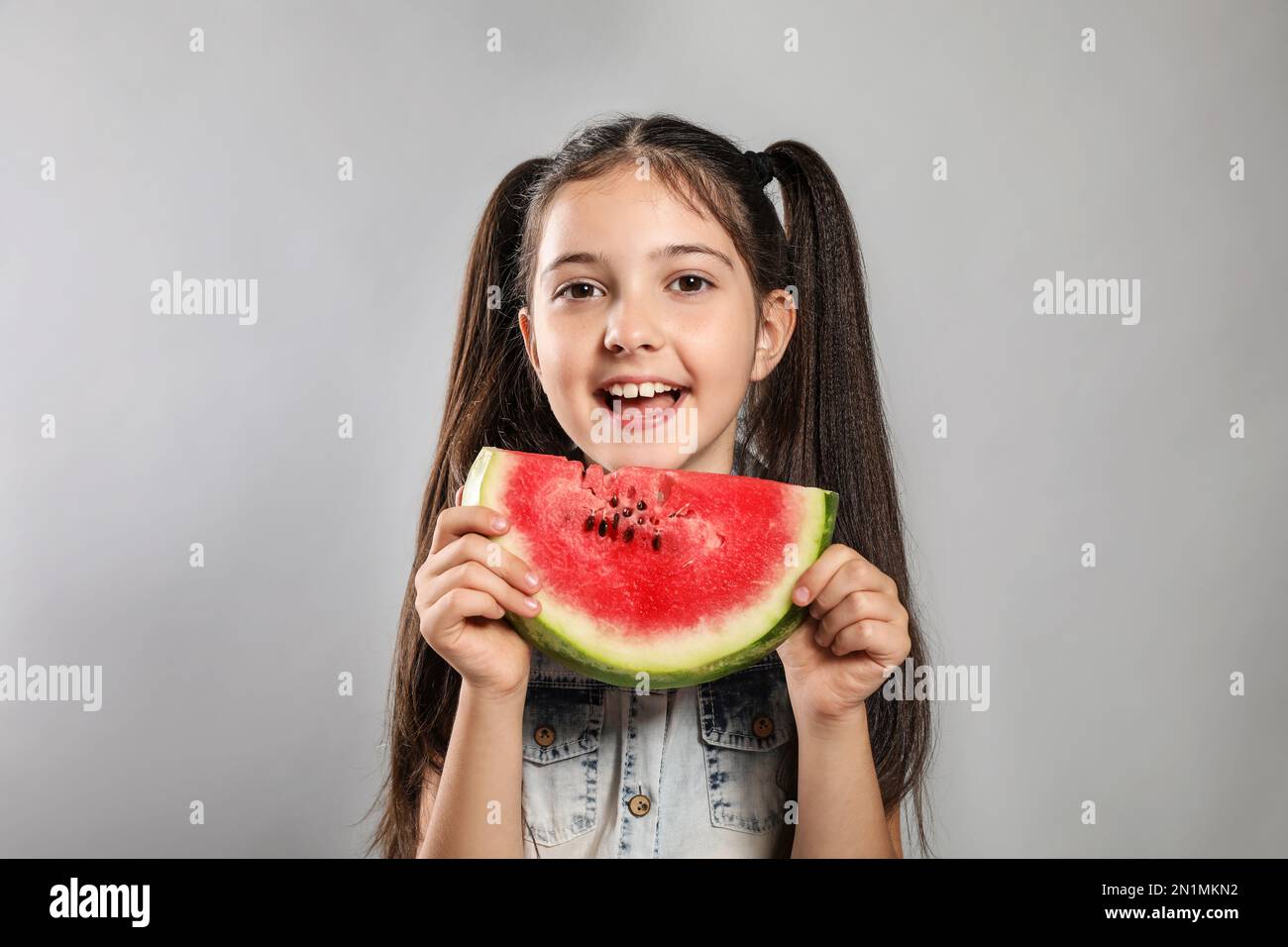 Cute little girl with watermelon on grey background Stock Photo - Alamy