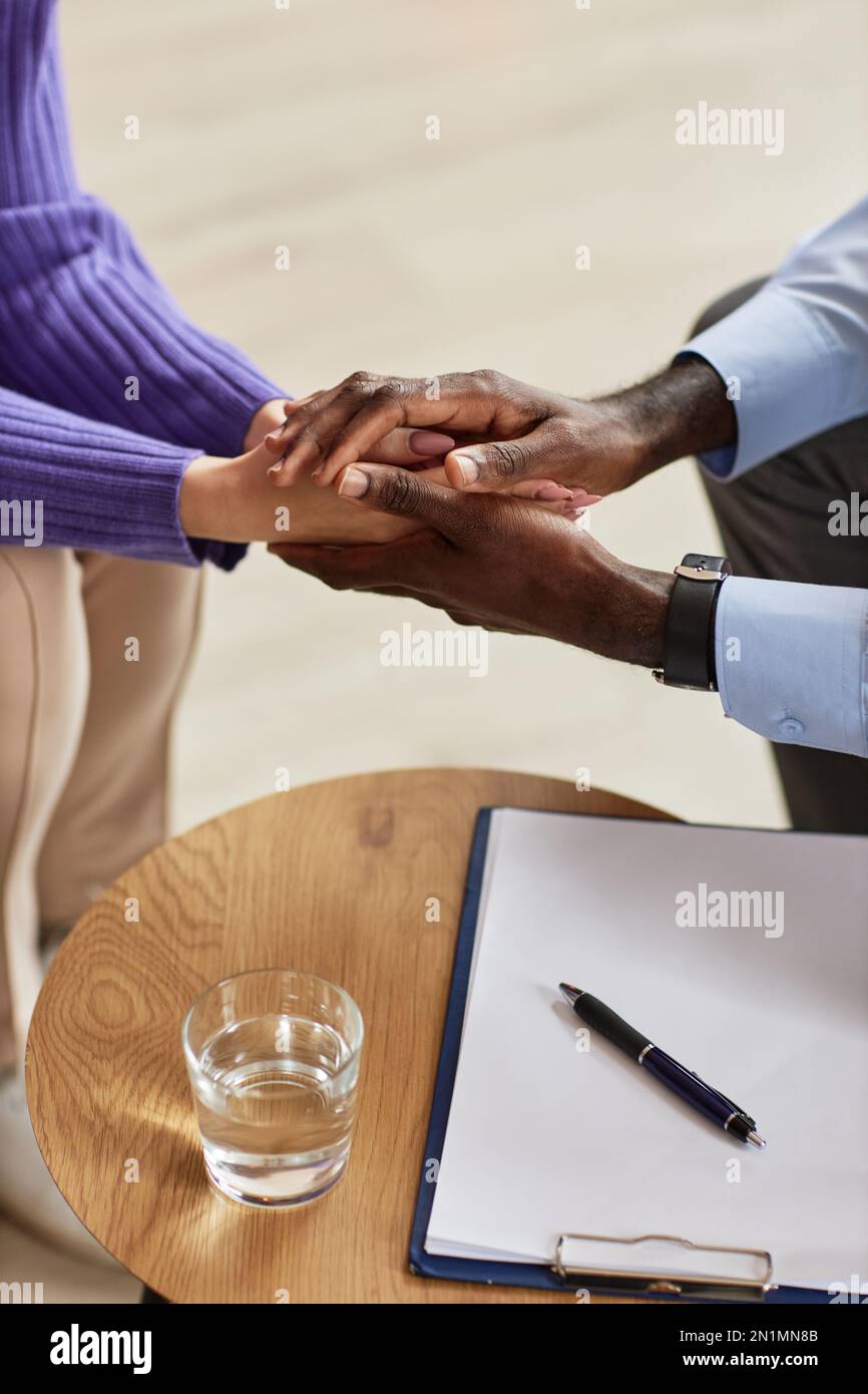 Therapist comforting client, holding her hands and telling words of ...
