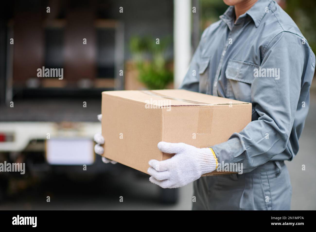 Mover with cardboard box standing in front of truck with opened Stock ...