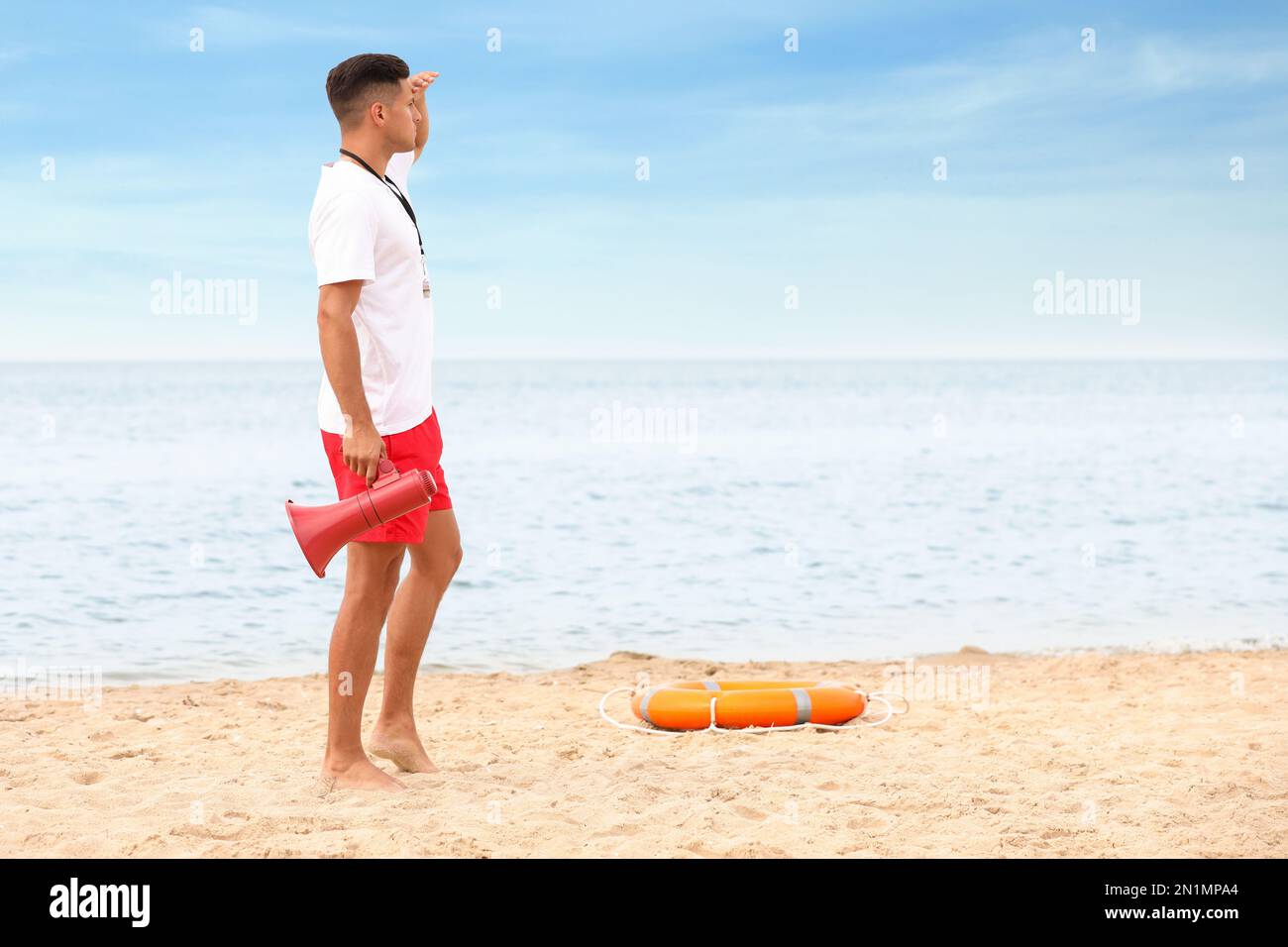 Handsome male lifeguard with megaphone at sandy beach Stock Photo - Alamy