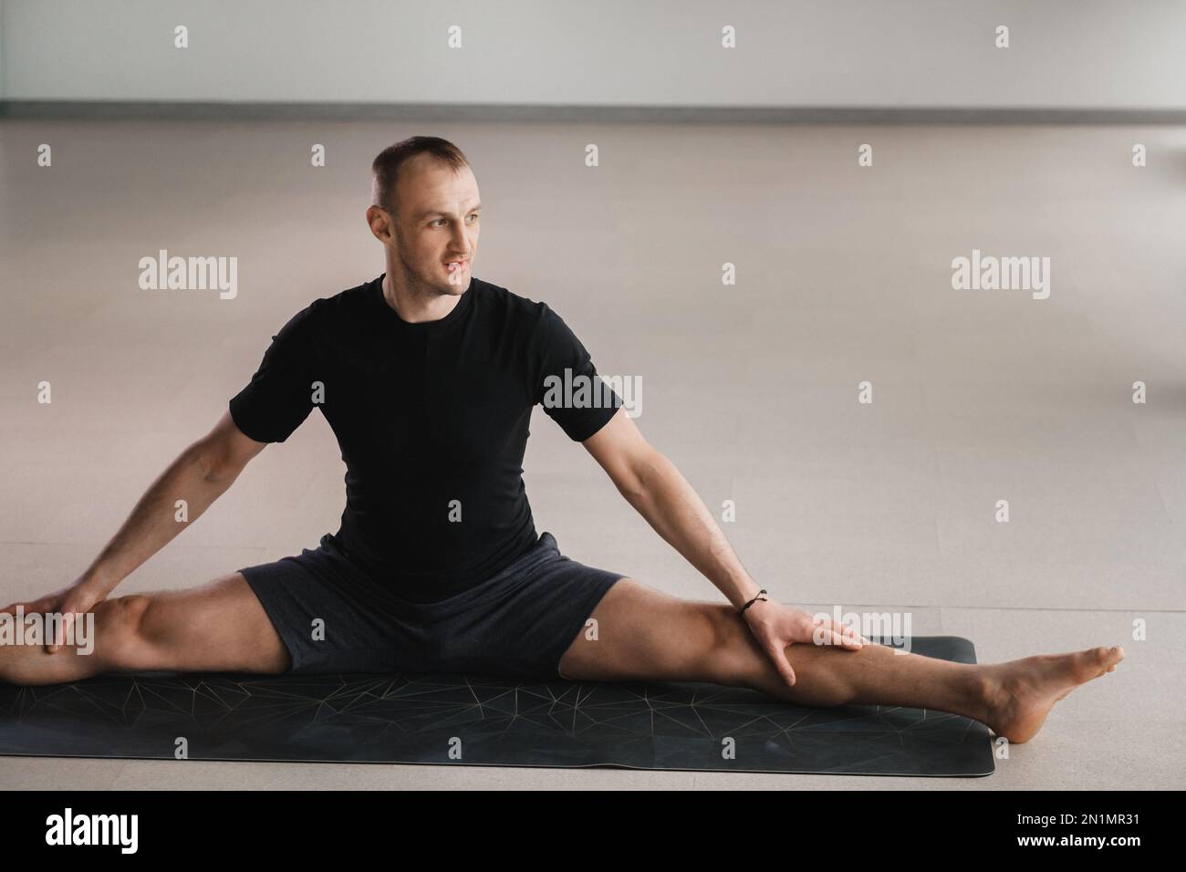 An athletically built man does yoga in the gym on a mat Stock Photo - Alamy