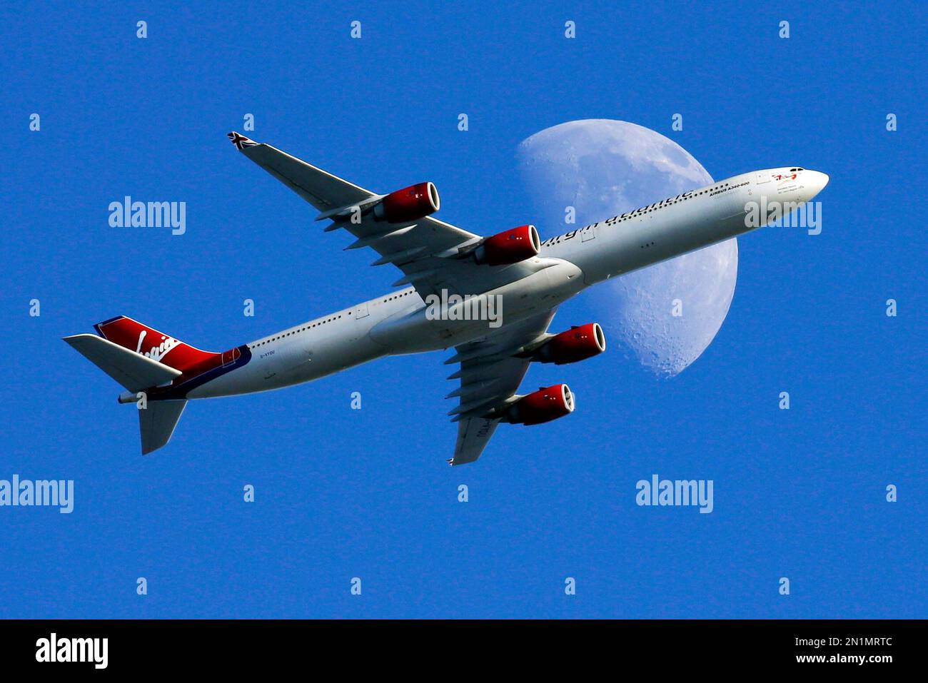 A Virgin Atlantic passenger plane crosses a waxing gibbous moon on its ...