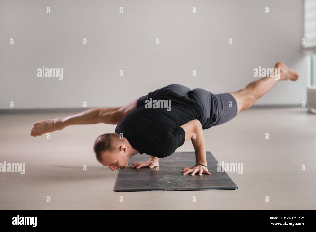 An athletically built man does yoga in the gym on a mat Stock Photo - Alamy