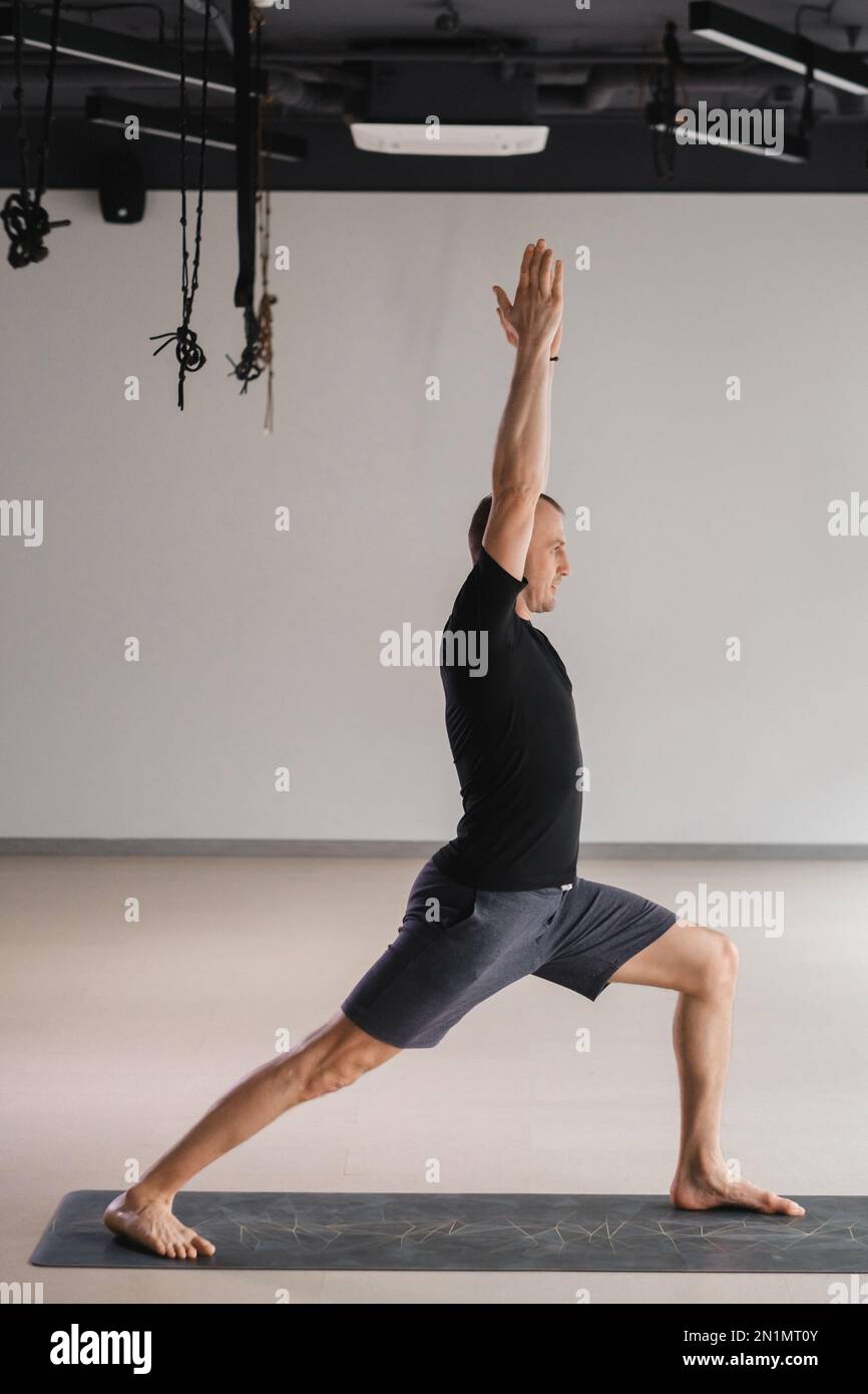 An athletically built man does yoga in the gym on a mat Stock Photo - Alamy
