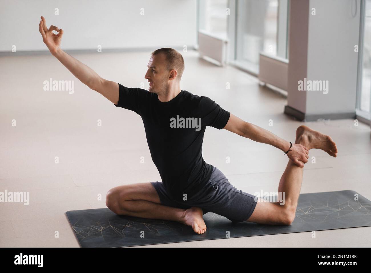 An athletically built man does yoga in the gym on a mat Stock Photo - Alamy