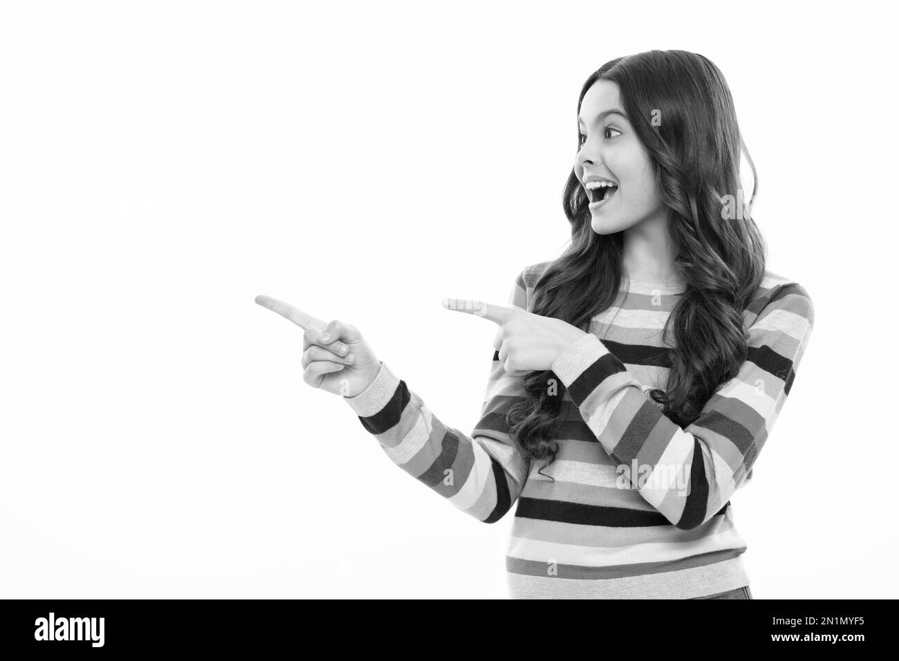 Positive teenager child points aside with cheerful expression, shows ...