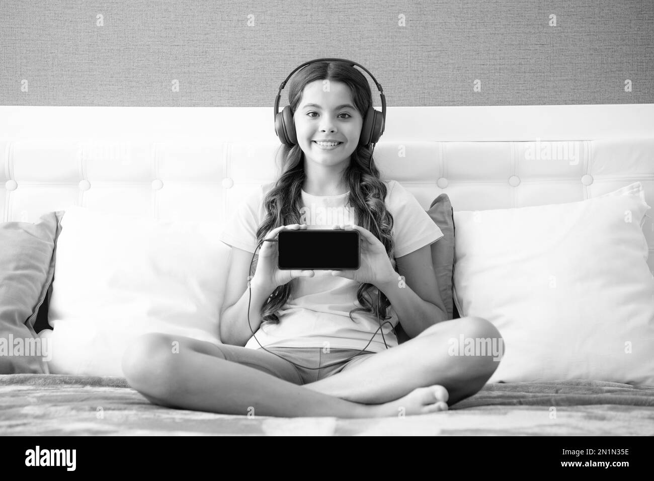 Teenager child girl showing screen phone wearing headphones listening ...