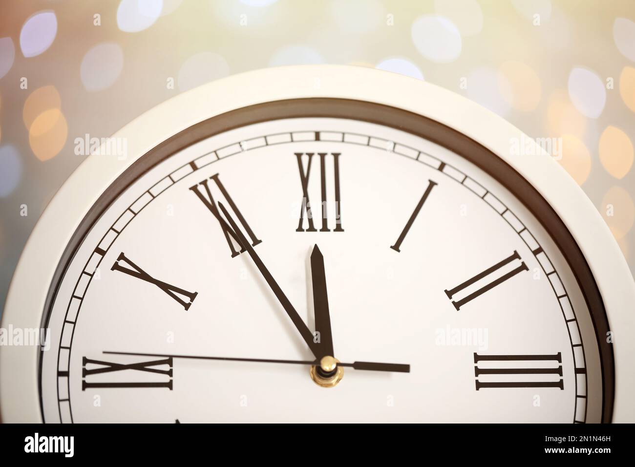 Clock showing five minutes until midnight on blurred background ...