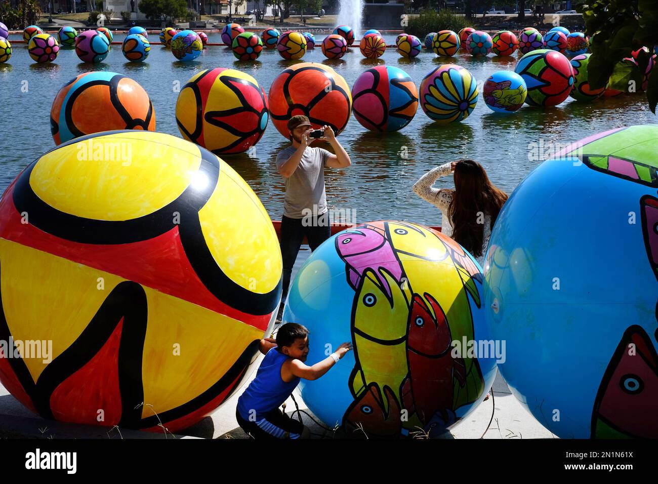 A couple takes photo with spheres in Los Angeles’ MacArthur Park Lake ...