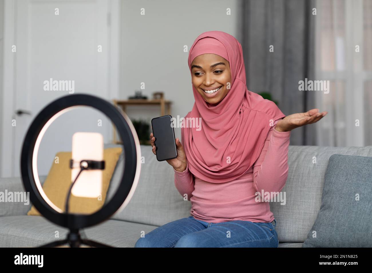 Modern work and hobby. Happy black muslim female blogger shooting video blog, making review on ...