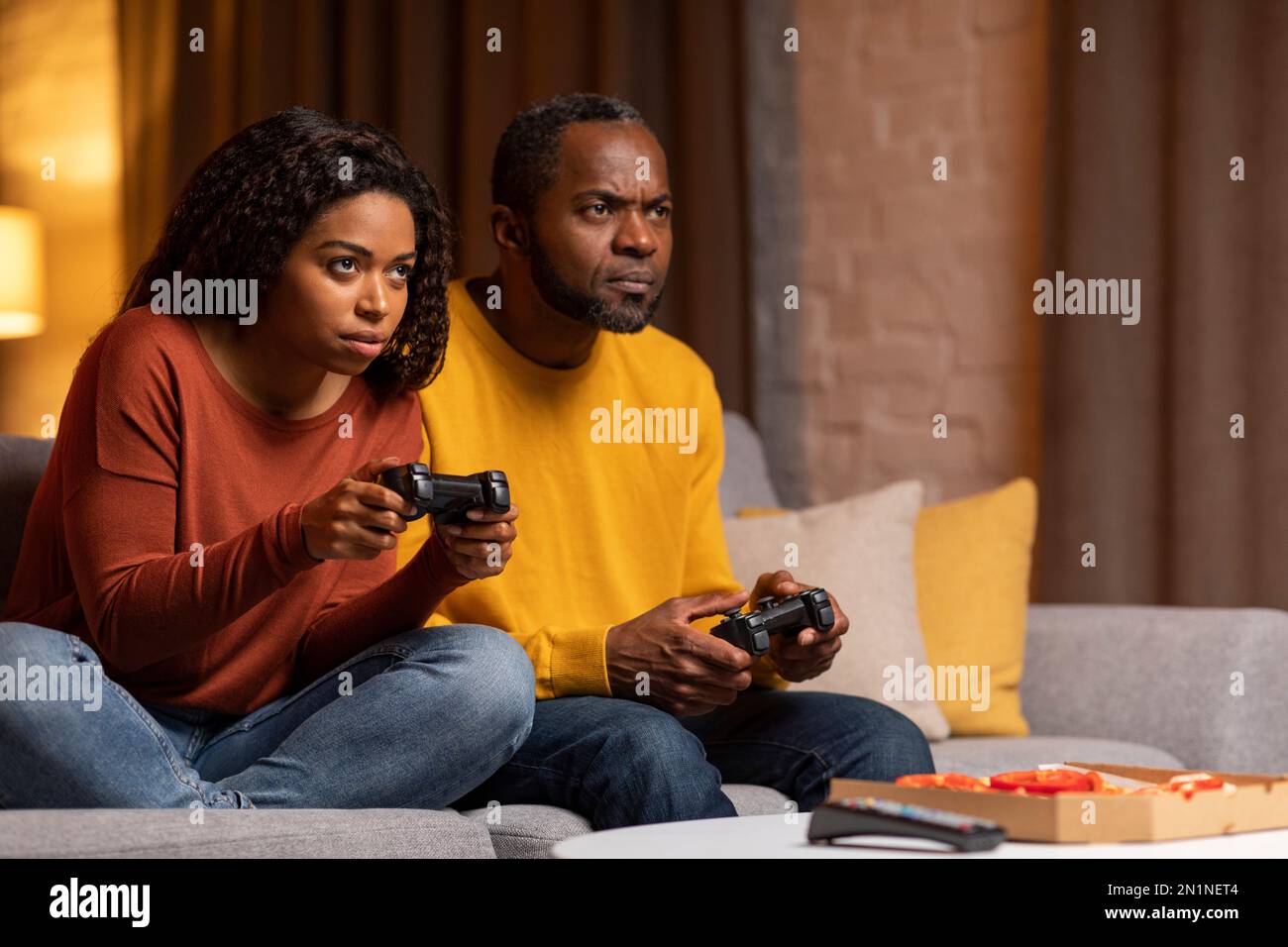 Concentrated black couple playing video games together Stock Photo - Alamy