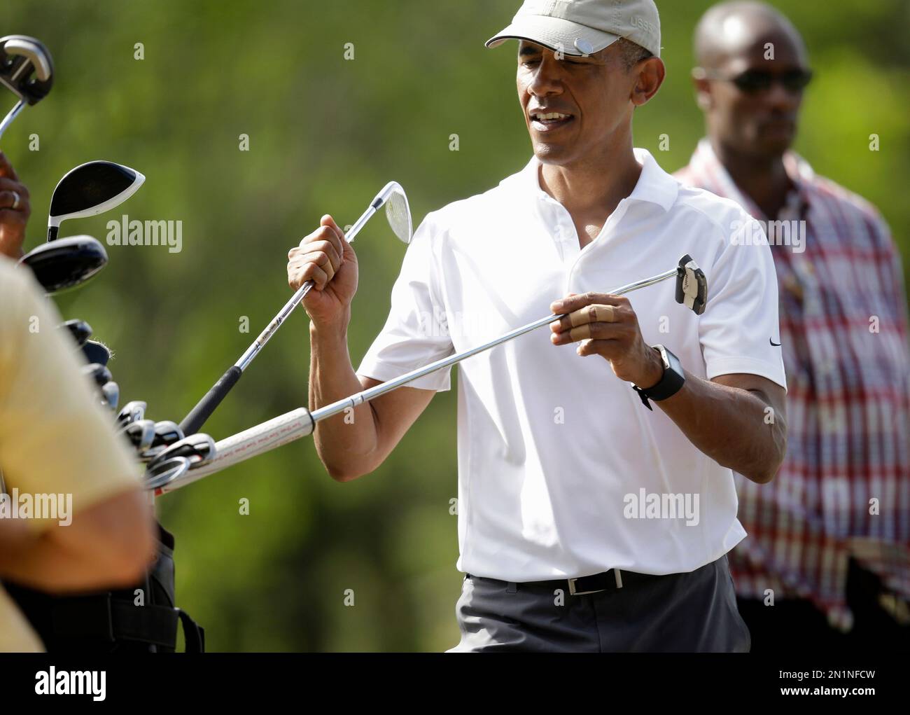 President Barack Obama returns clubs to a golf cart while golfing ...