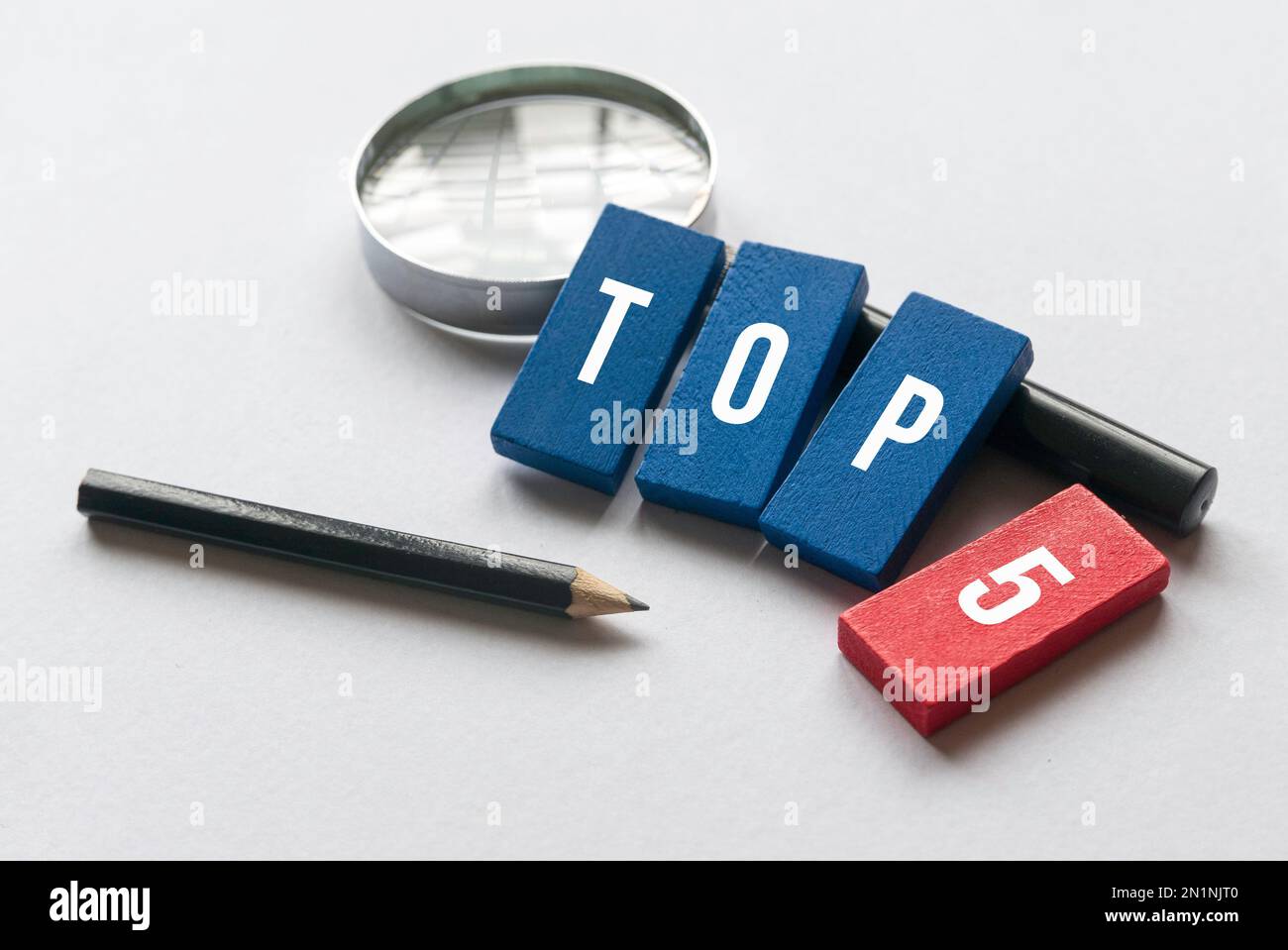 Pencil, magnifying glass and wooden block written with Top 5 on white ...