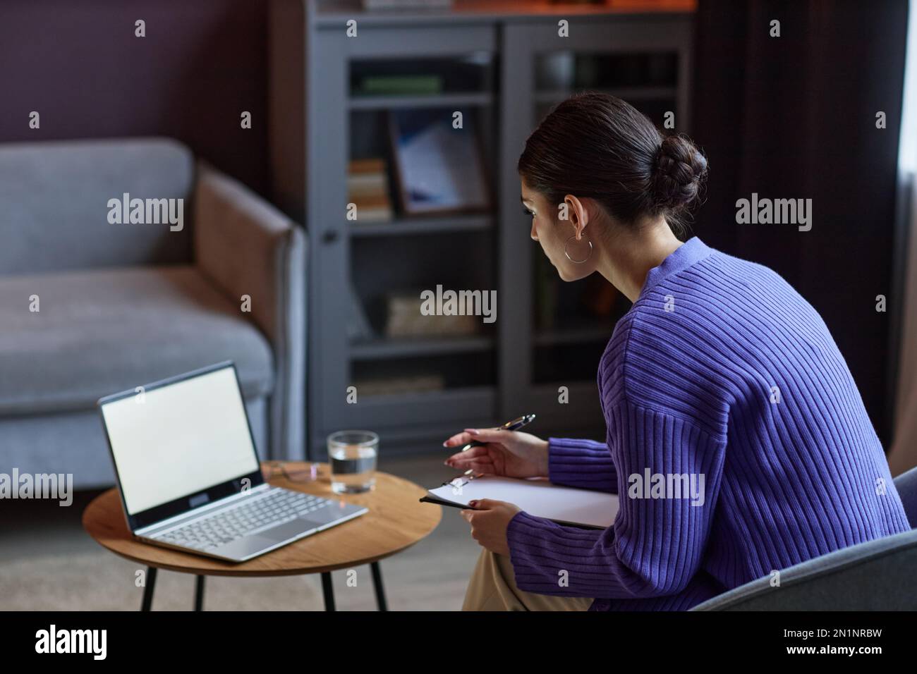 Psychologist having online session with client and writing down ...