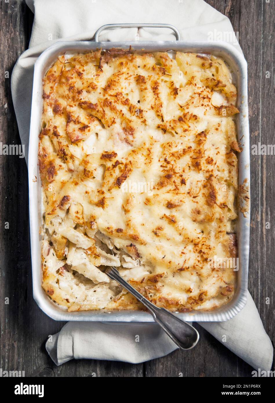 Mac and cheese recipe.Grey wooden old table, white towel, silver baking ...