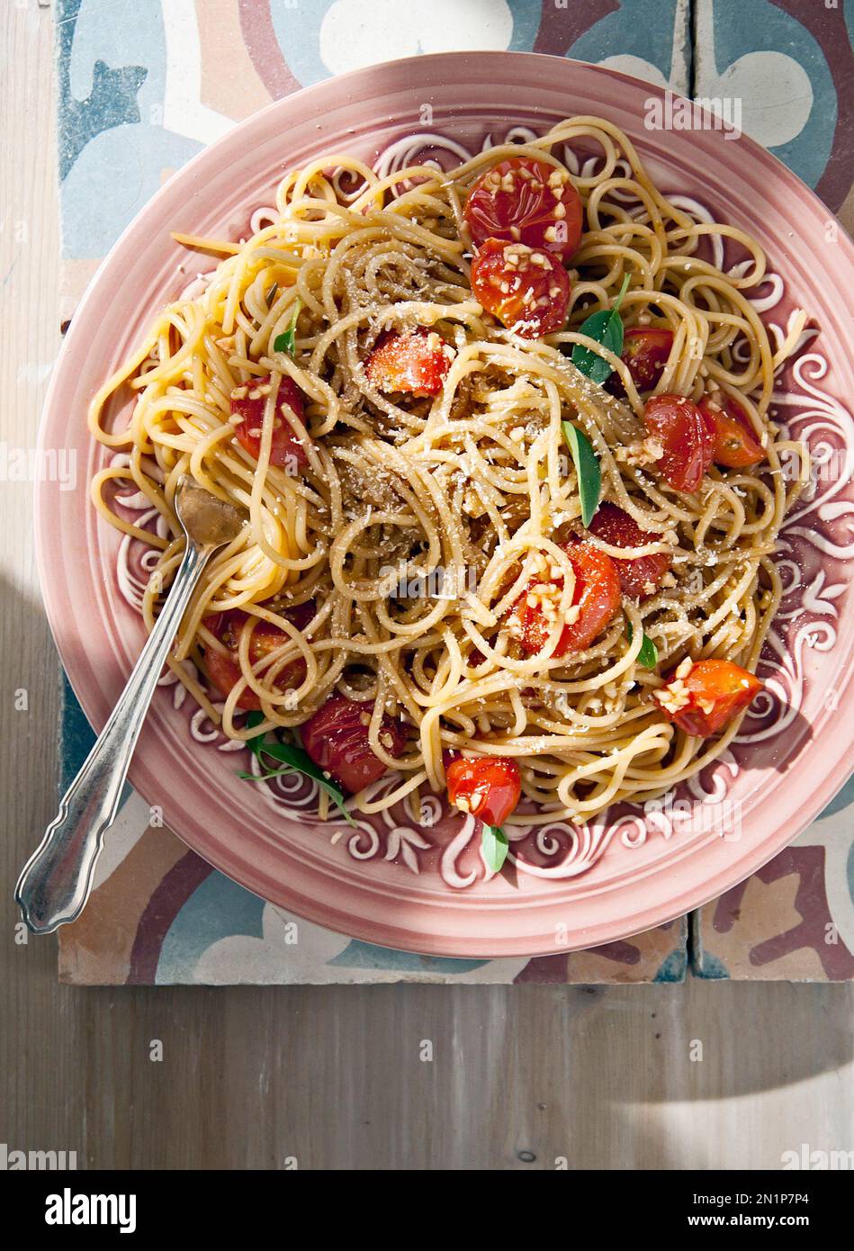 Spaghetti with cherry tomatoes, grape syrup, basil leafs. Pink plate ...