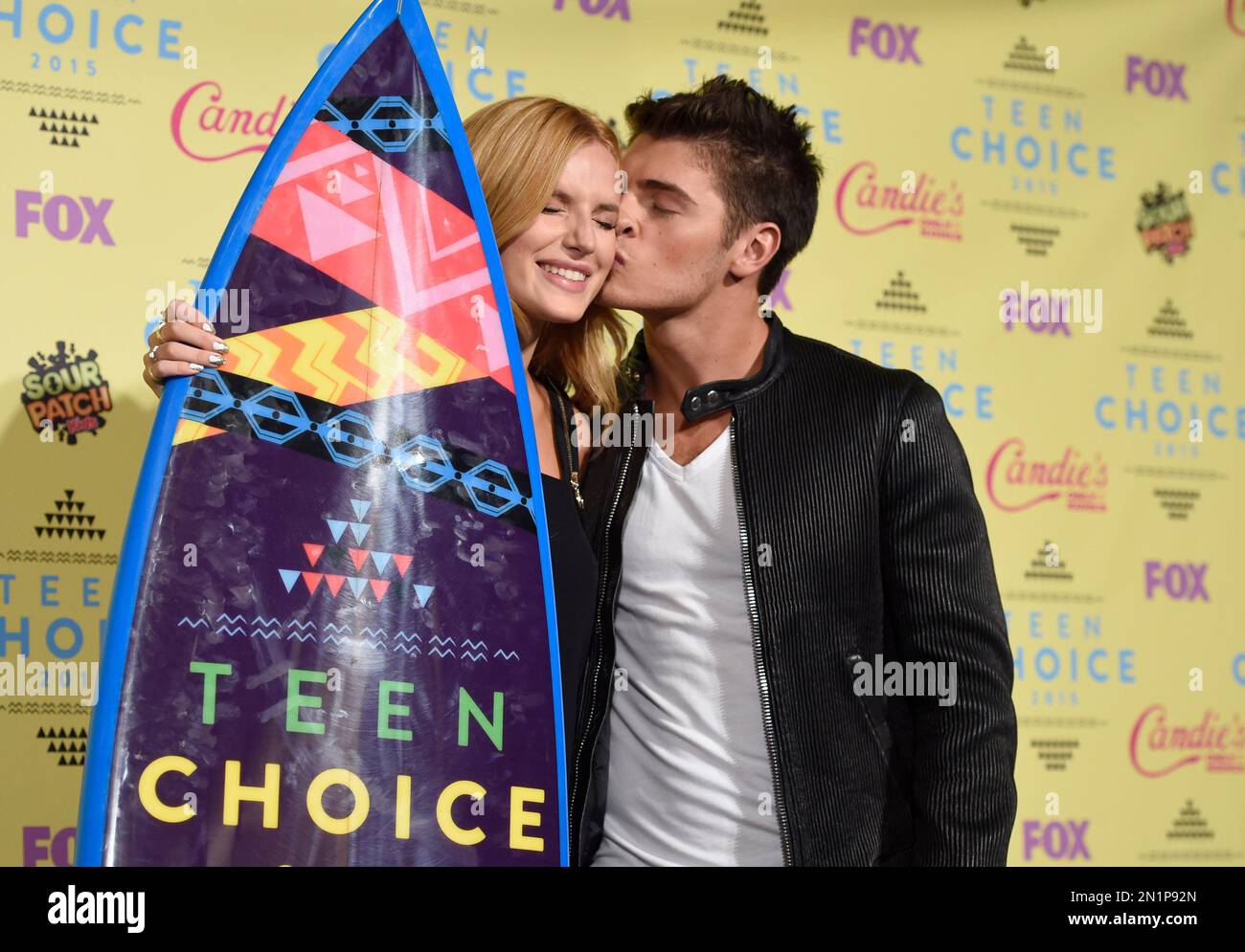 Gregg Sulkin, right, kisses Bella Thorne in the press room at the Teen ...