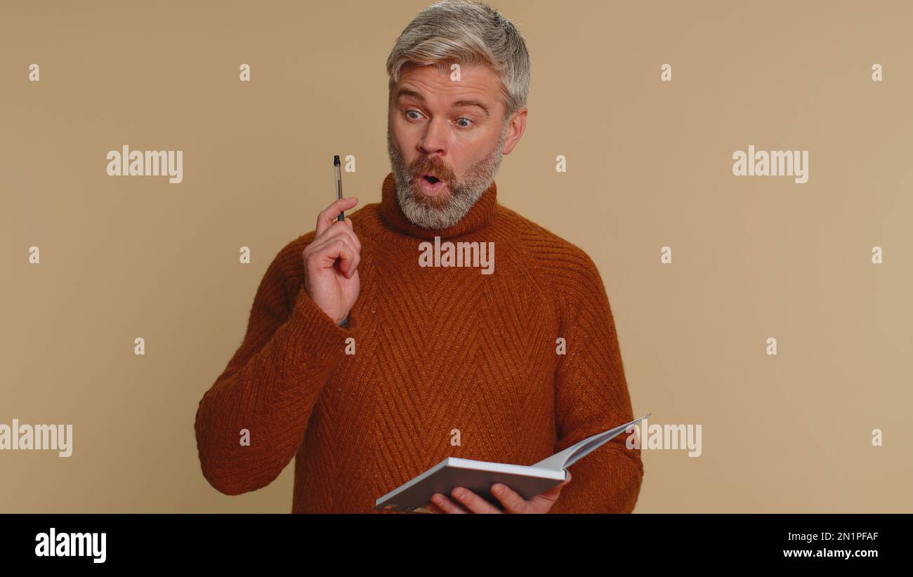 Thoughtful journalist middle-aged old man making notes, writing down ...