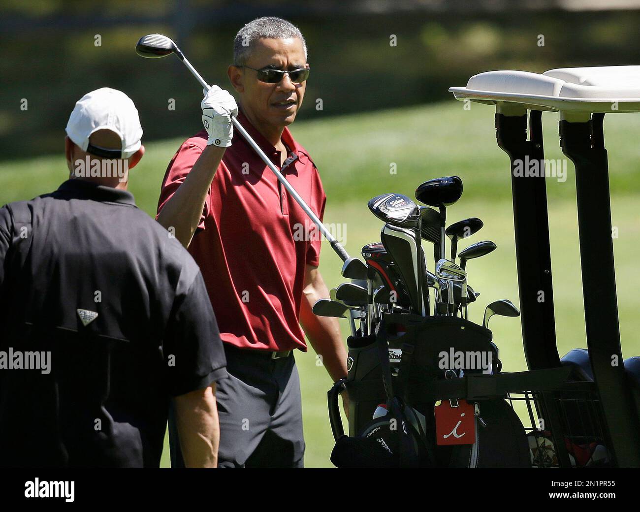 President Barack Obama returns a club to the cart while golfing, Friday ...