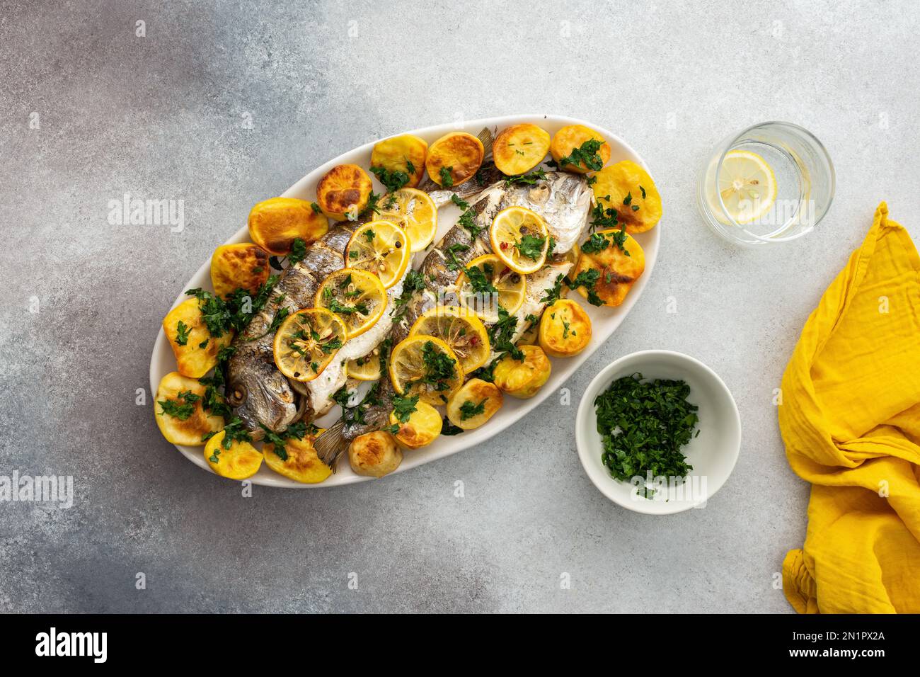 Oven-baked Dorada fish with potatoes and lemon slices, sprinkled with ...