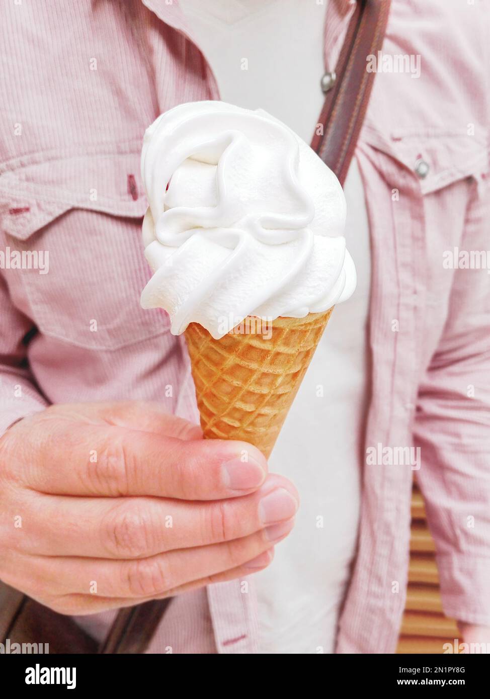 Man in light red shirt holds big tasty waffle cone with ice-cream. Cold ...