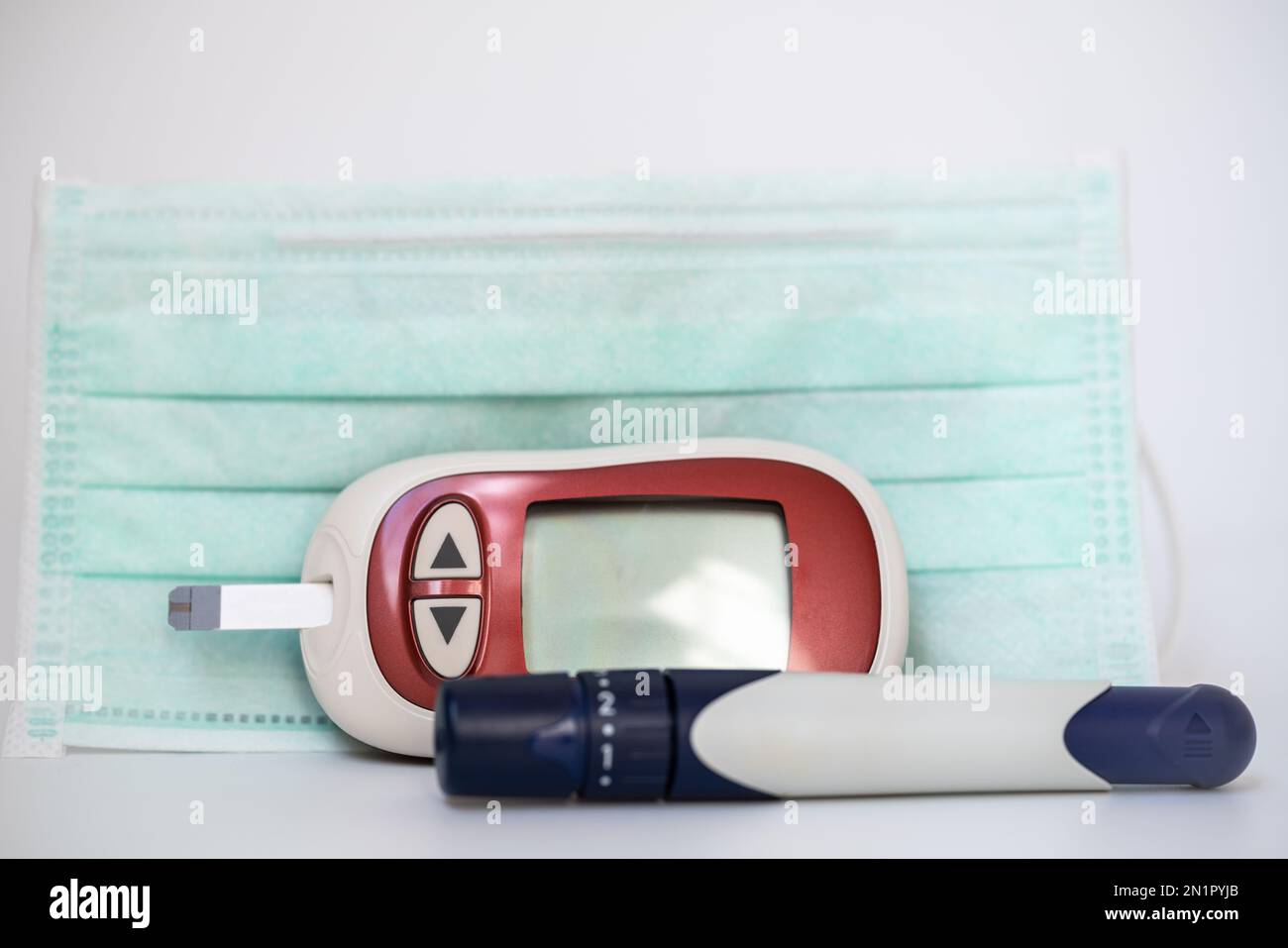 Closeup of Glucose meter with lancet and surgical face mask as ...