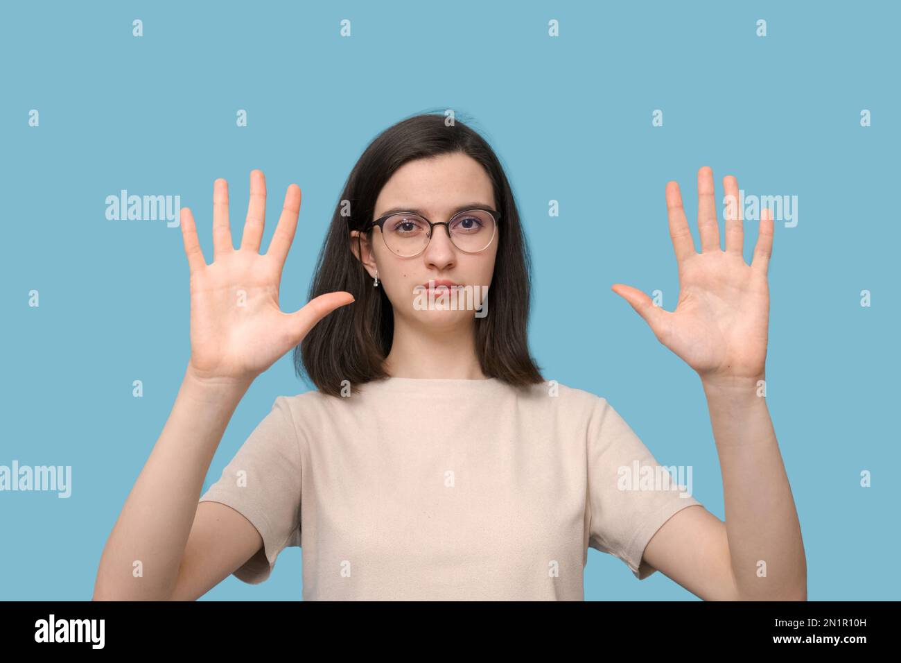 Portrait of a student girl with glasses and a beige blouse showing two ...