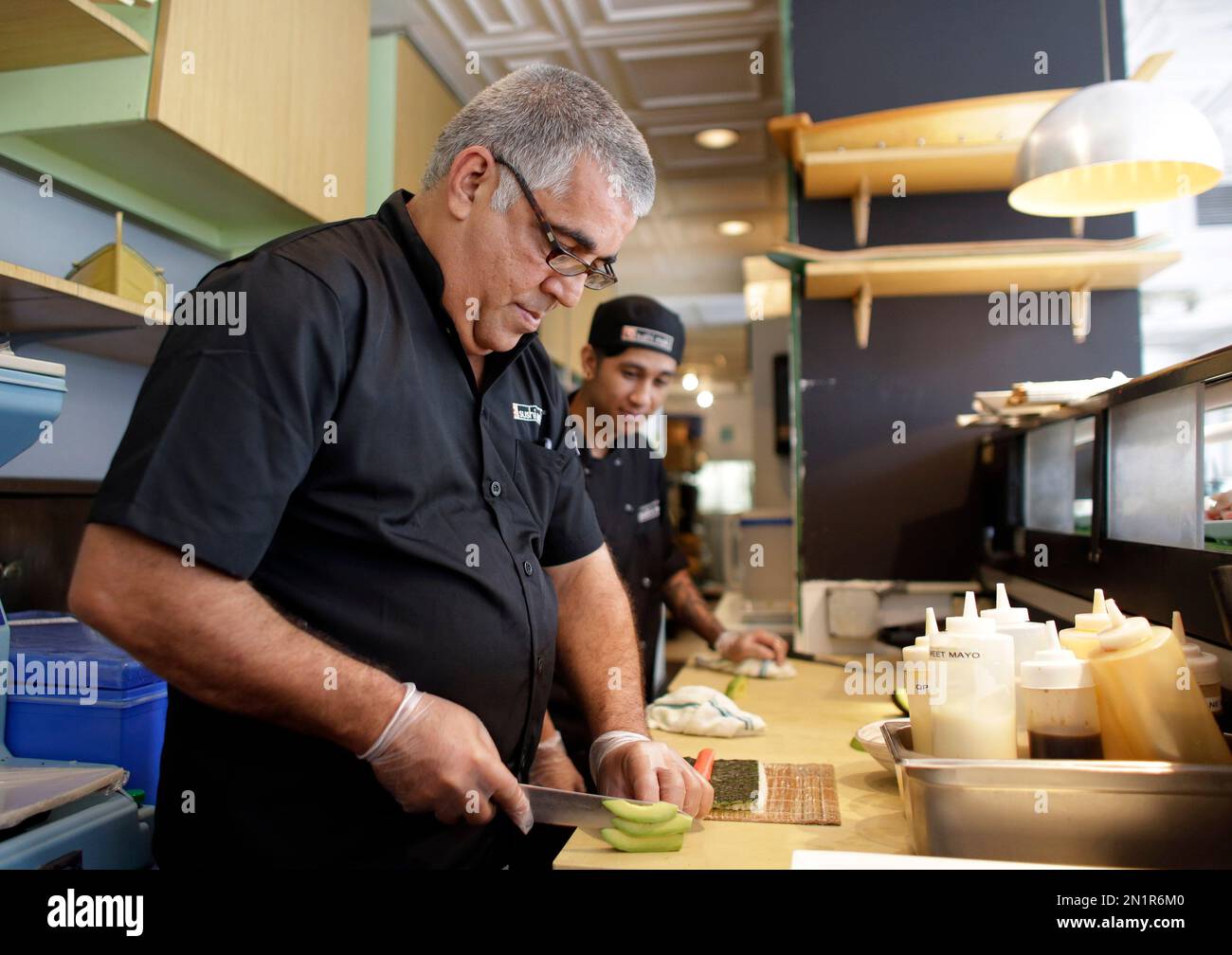 Chef Lucio Alfonso Perez, of Cuba, left, slices avocado for a sushi ...