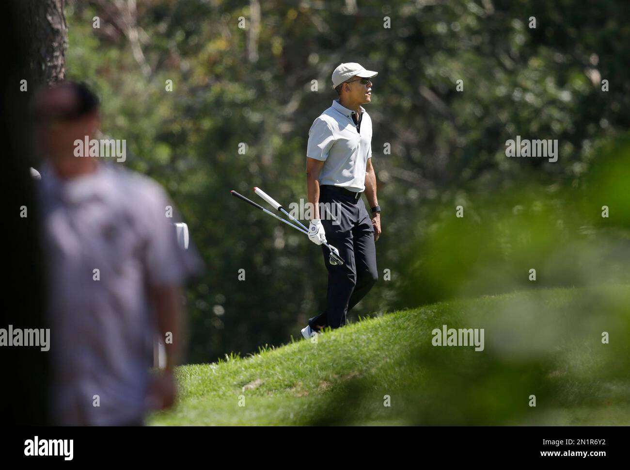President Barack Obama carries clubs as he walks toward a green while ...