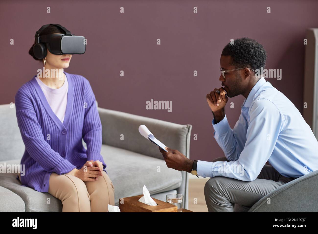 Psychologist asking female client in virtual reality headset some ...