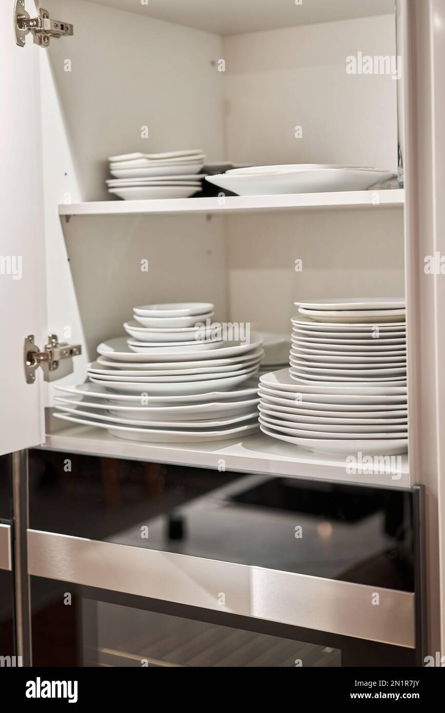 Glasses, dishes and bowls in a cabinet in a kitchen. Kitchen storage ...