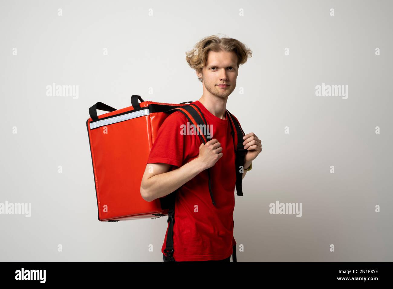 Young courier delivery man in red uniform with thermo bag isolated on ...