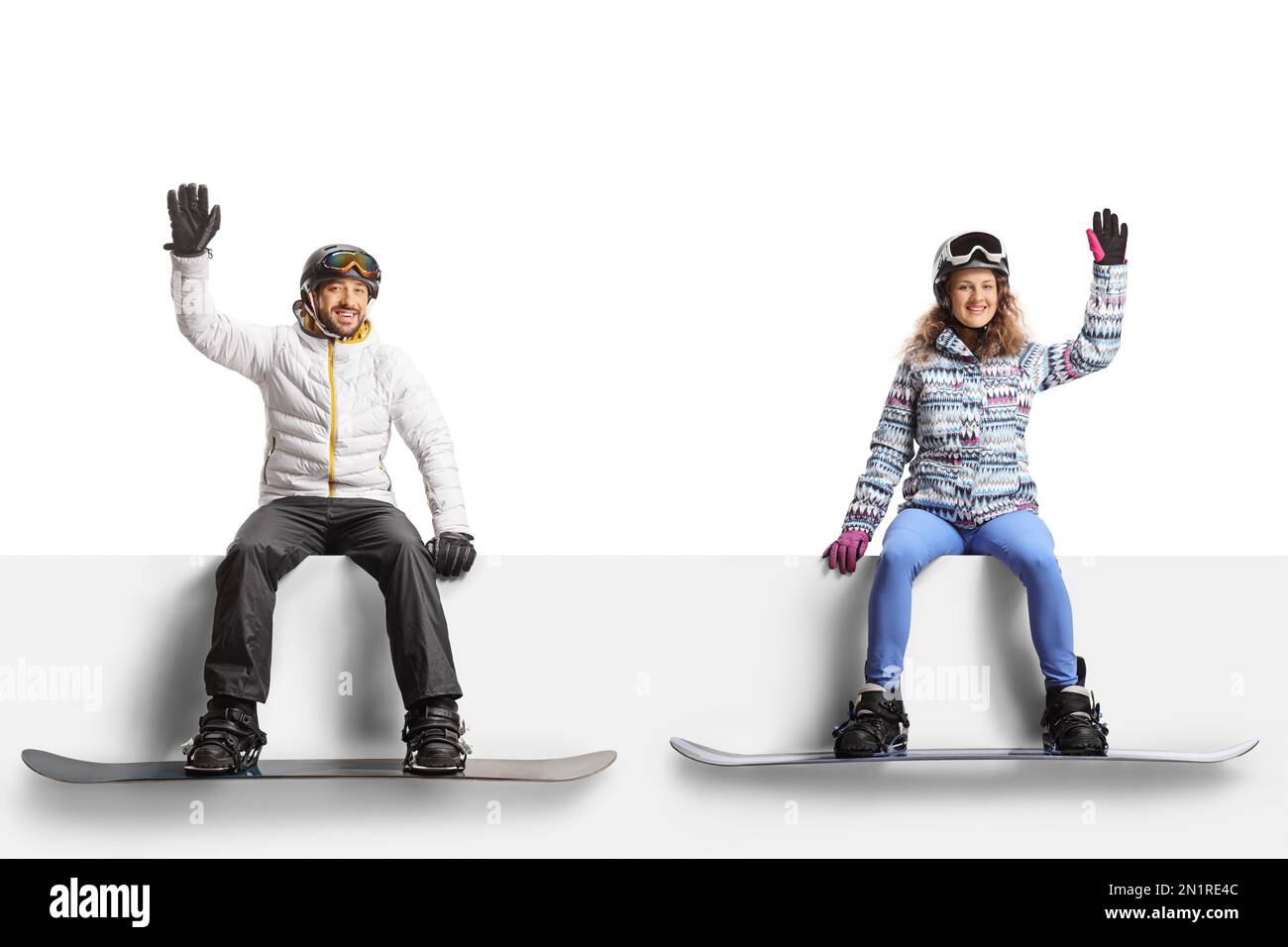 Young man and woman with snowboards sitting on a blank panel and waving ...