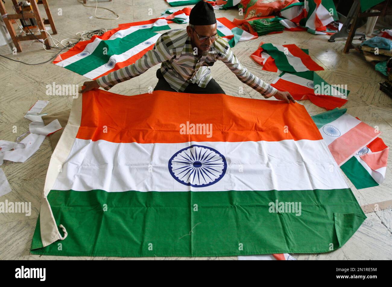 An Indian man prepares to fold an Indian flag being made at a factory ...