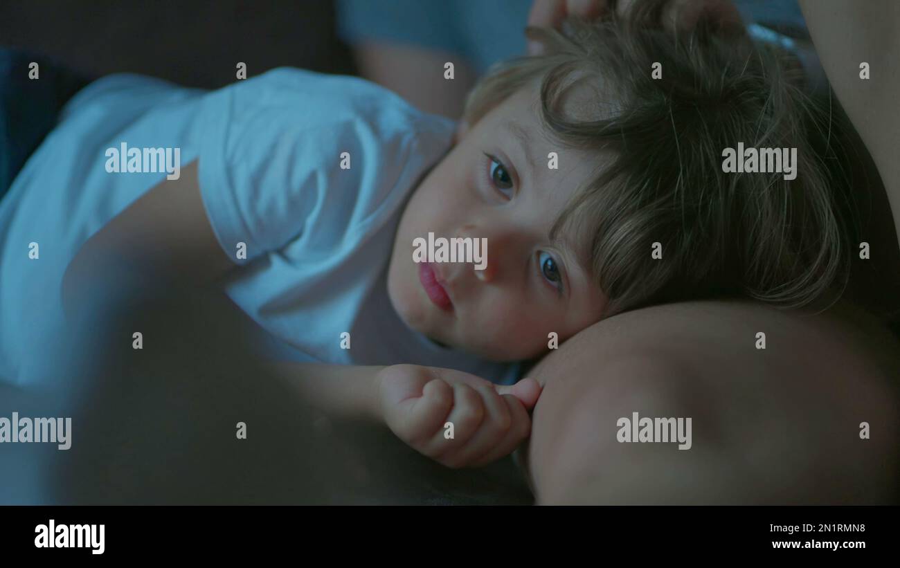 Cute little boy lying down on mother leg. Closeup face of child hair ...