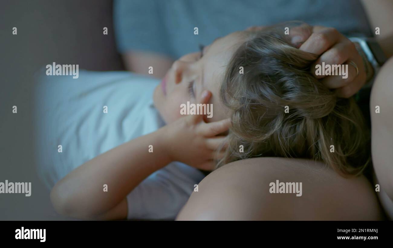 Cute little boy lying down on mother leg. Closeup face of child hair ...