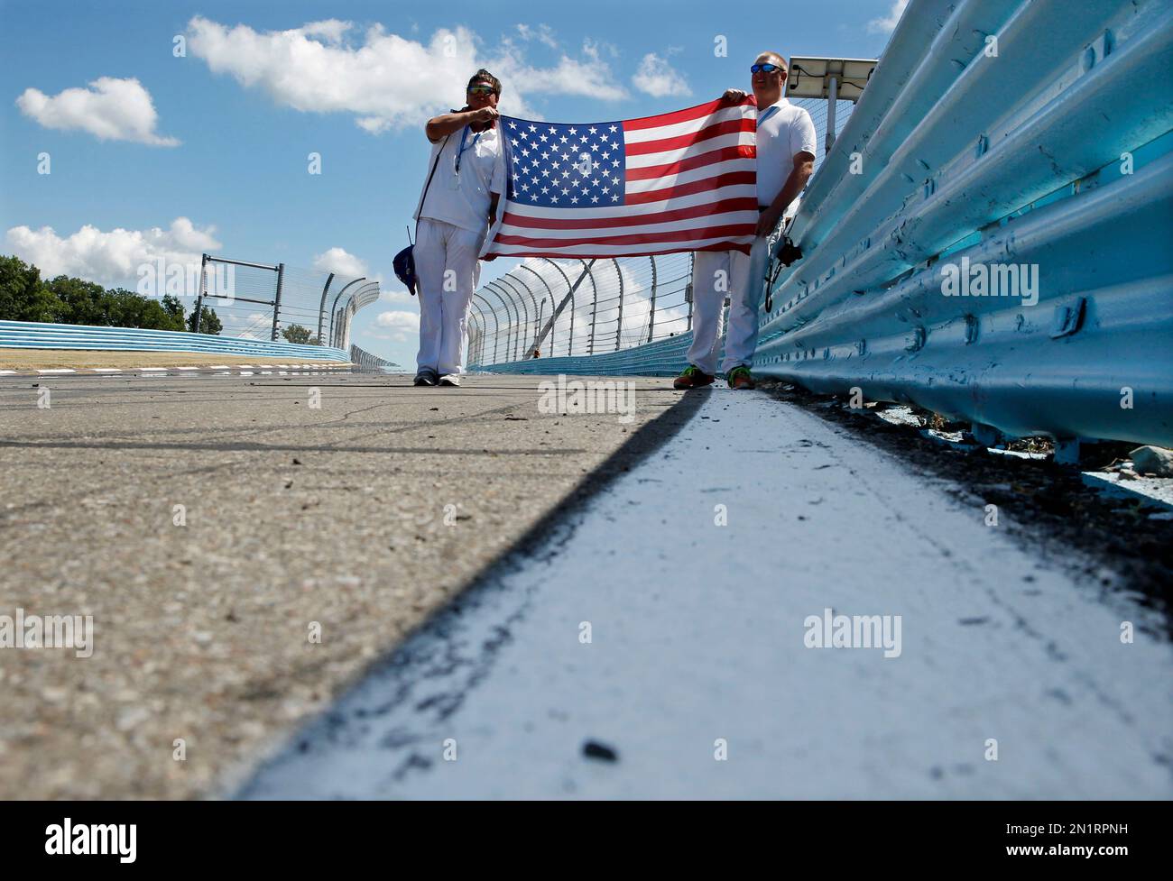 Track corner workers hold a United States flag as they stand on the ...