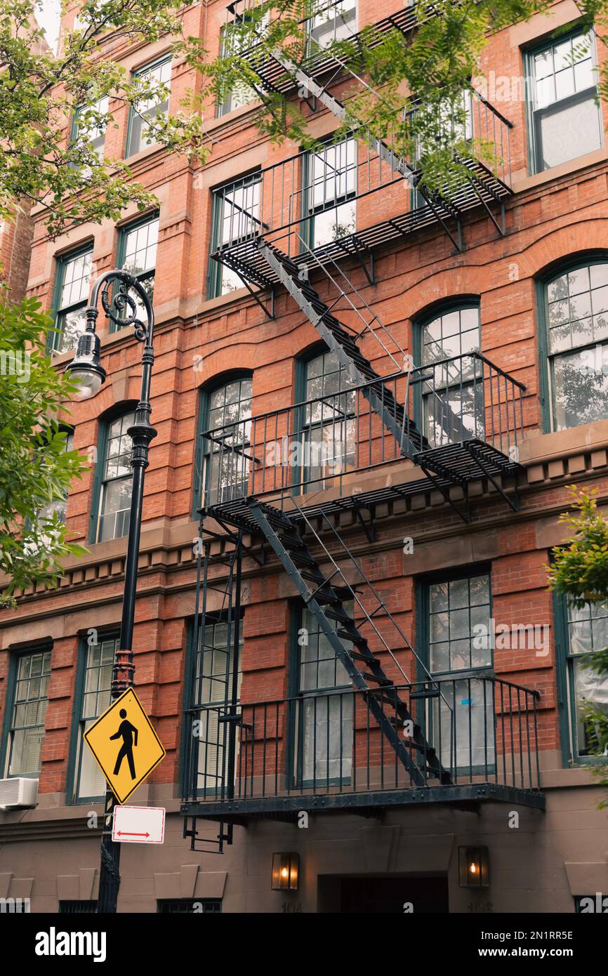 brick building with metal balconies and fire escape stairs near lantern ...