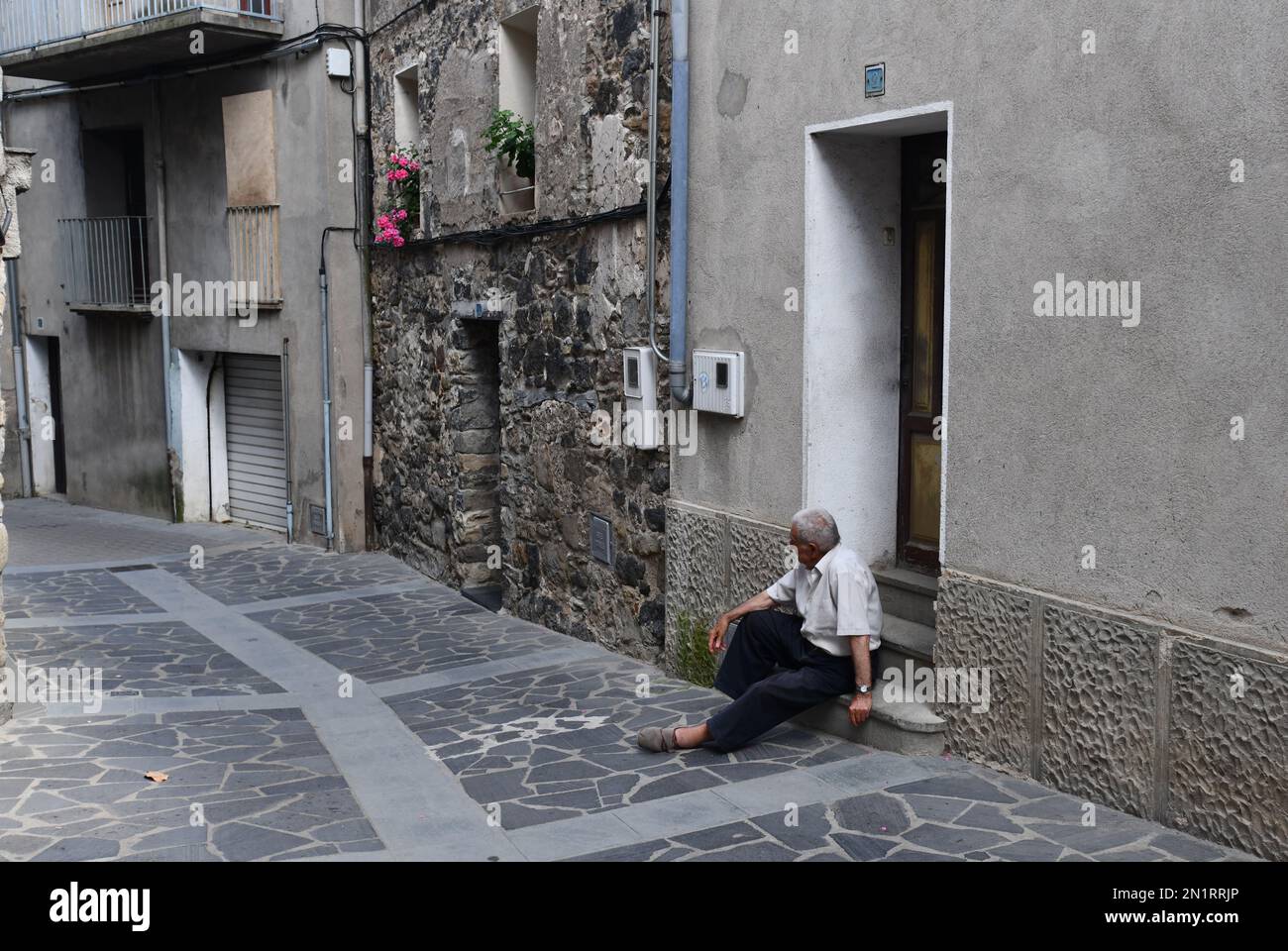 Old man sitting on his doorstep in the streets Castellfollit de la Roca ...