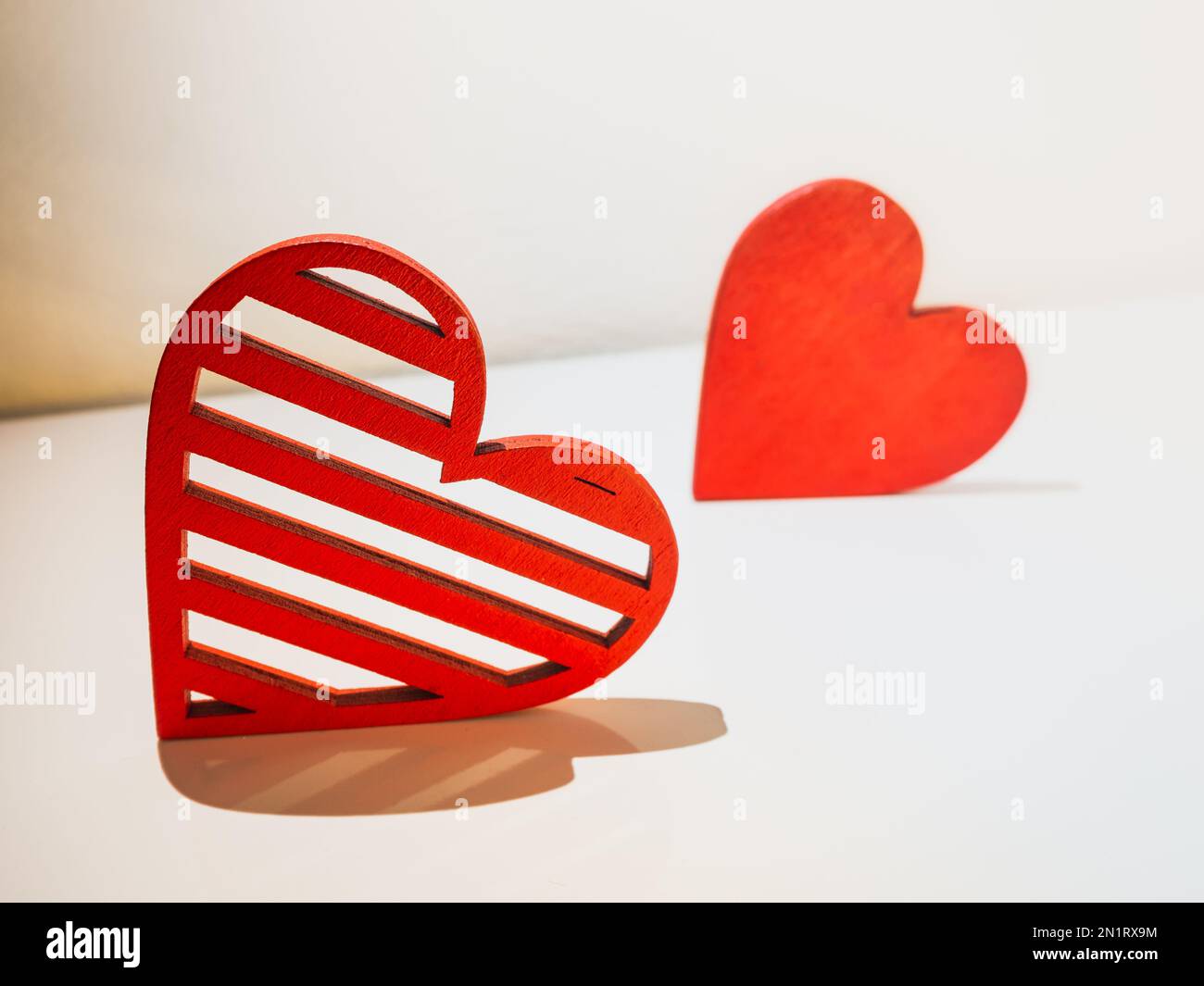 Red wooden heart concept on light background with heart shadow ...