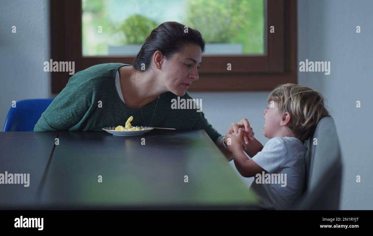 Child hitting hand and crying in front mother seated at lunch table ...